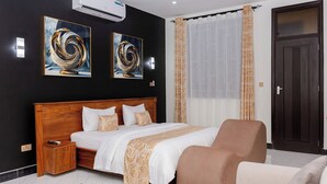 Quarto moderno com cama de madeira, mesa de cabeceira, sofá e duas pinturas abstratas na parede.