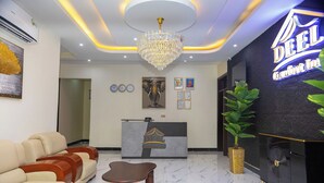 Uma área de recepção de hotel com um candelabro, um balcão de atendimento, um sofá e uma mesa de centro.