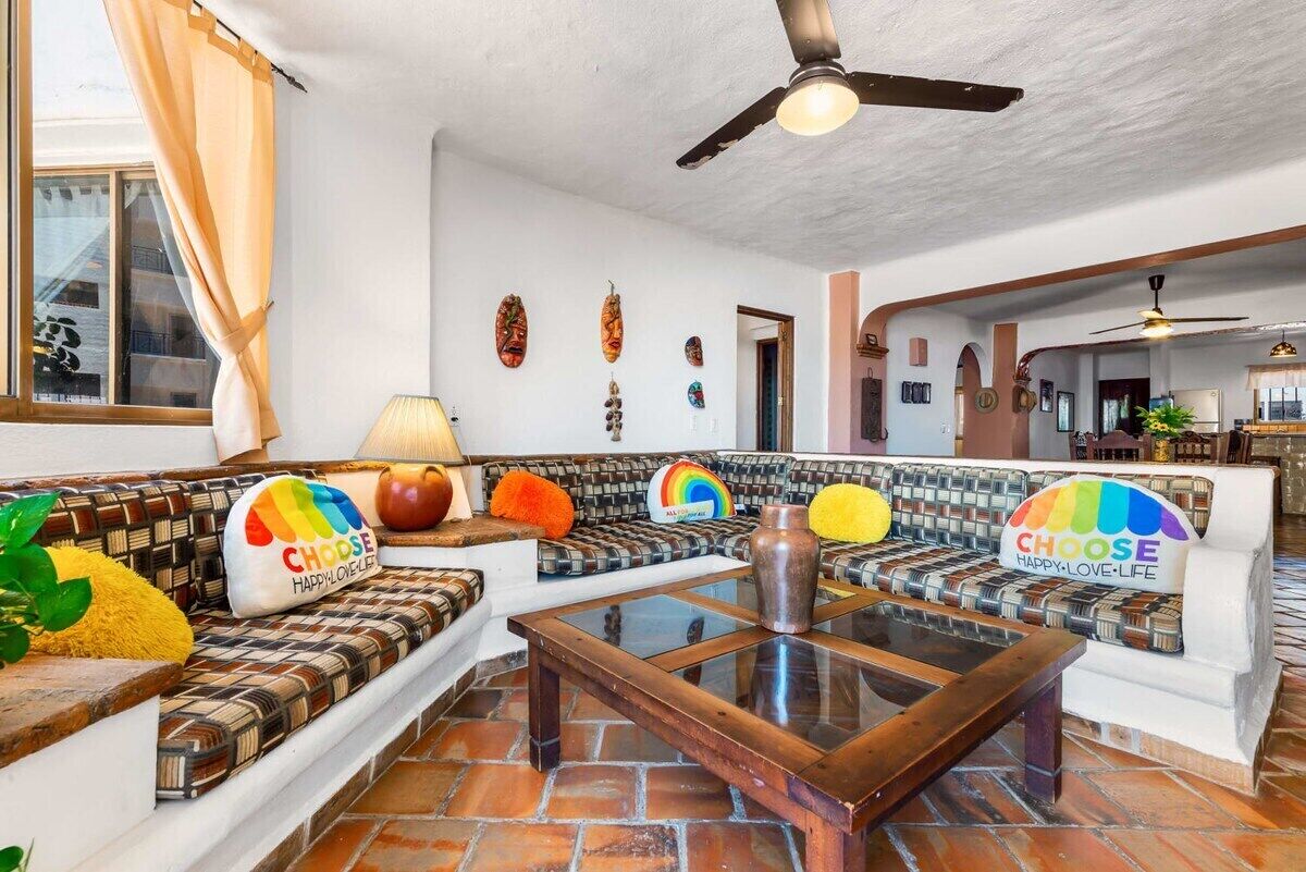 Uma sala de estar com sofá, mesa de centro e ventoinha no teto.