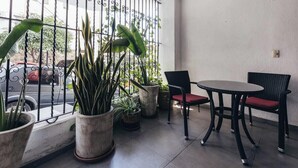 Varanda com vasos de plantas, uma mesa e duas cadeiras.