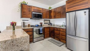 Uma cozinha moderna com bancadas de granito, eletrodomésticos de aço inoxidável e armários de madeira.