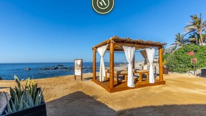 Um gazebo à beira-mar com vista para o oceano, uma placa de sinalização e um vaso de planta.
