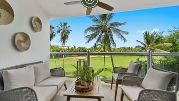 Varanda com móveis de vime, ventilador de teto e vista para um campo de golfe.