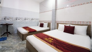 Quarto de hotel com duas camas, paredes de mármore e uma pequena mesa com um vaso.