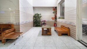 Um interior moderno com um banco de madeira, uma pequena mesa com um vaso de flores e uma planta de bambu.