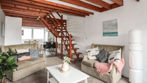 Sala de estar com dois sofás, uma mesa de centro e uma escada de madeira.