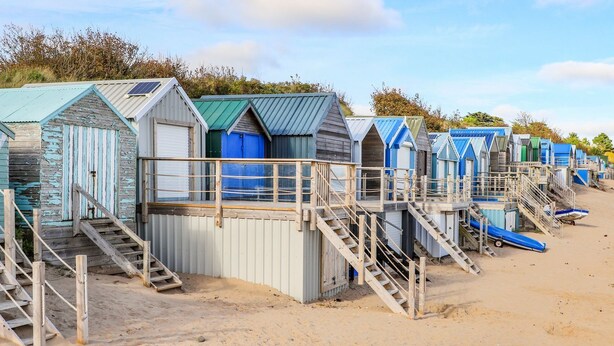 Fileira de cabanas de praia com escadas de madeira que dão para a praia.