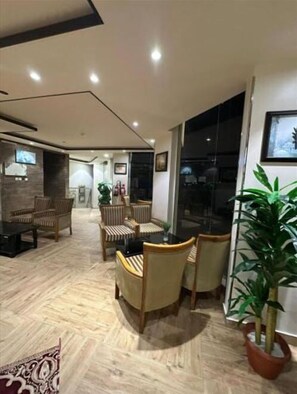 Uma sala de estar moderna com uma janela grande, uma área de jantar com cadeiras listradas e uma planta em vaso.