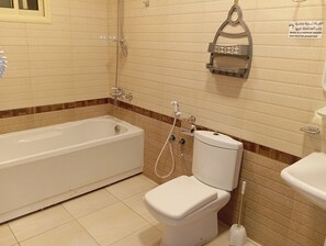 Uma casa de banho com banheira, sanita e chuveiro.