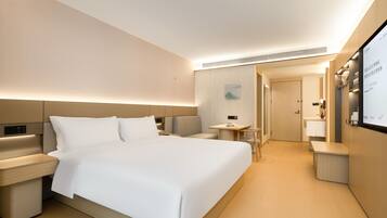 Quarto de hotel moderno com cama grande, mesas de cabeceira, escrivaninha e espelho.