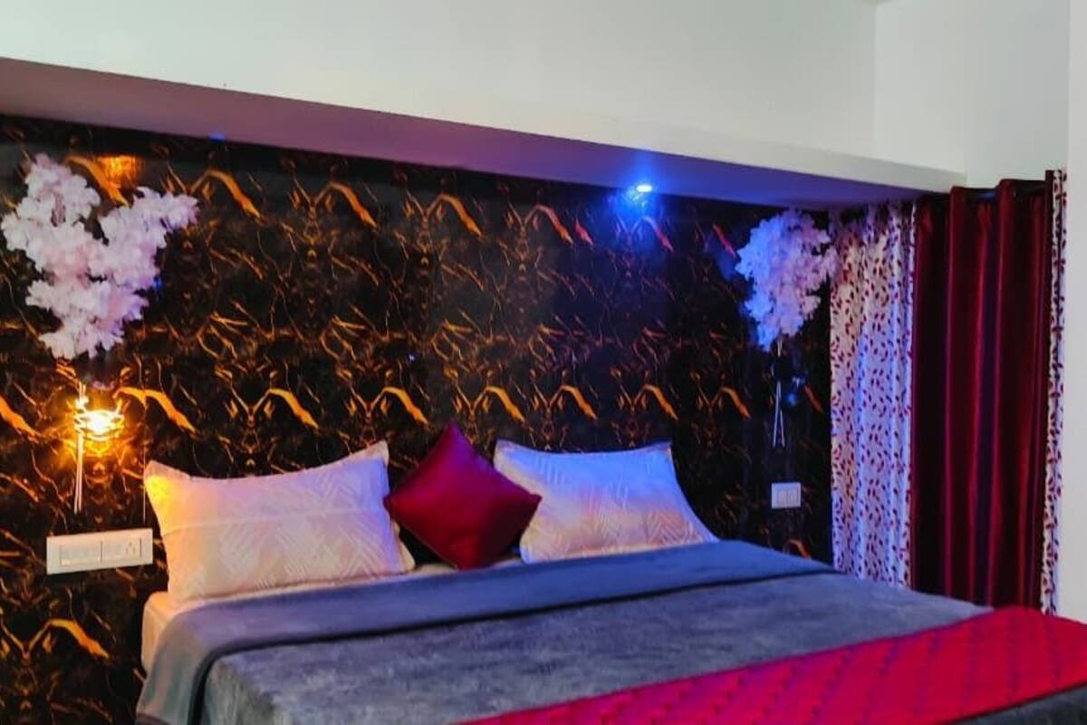 Quarto com cama, almofadas e uma parede decorativa.