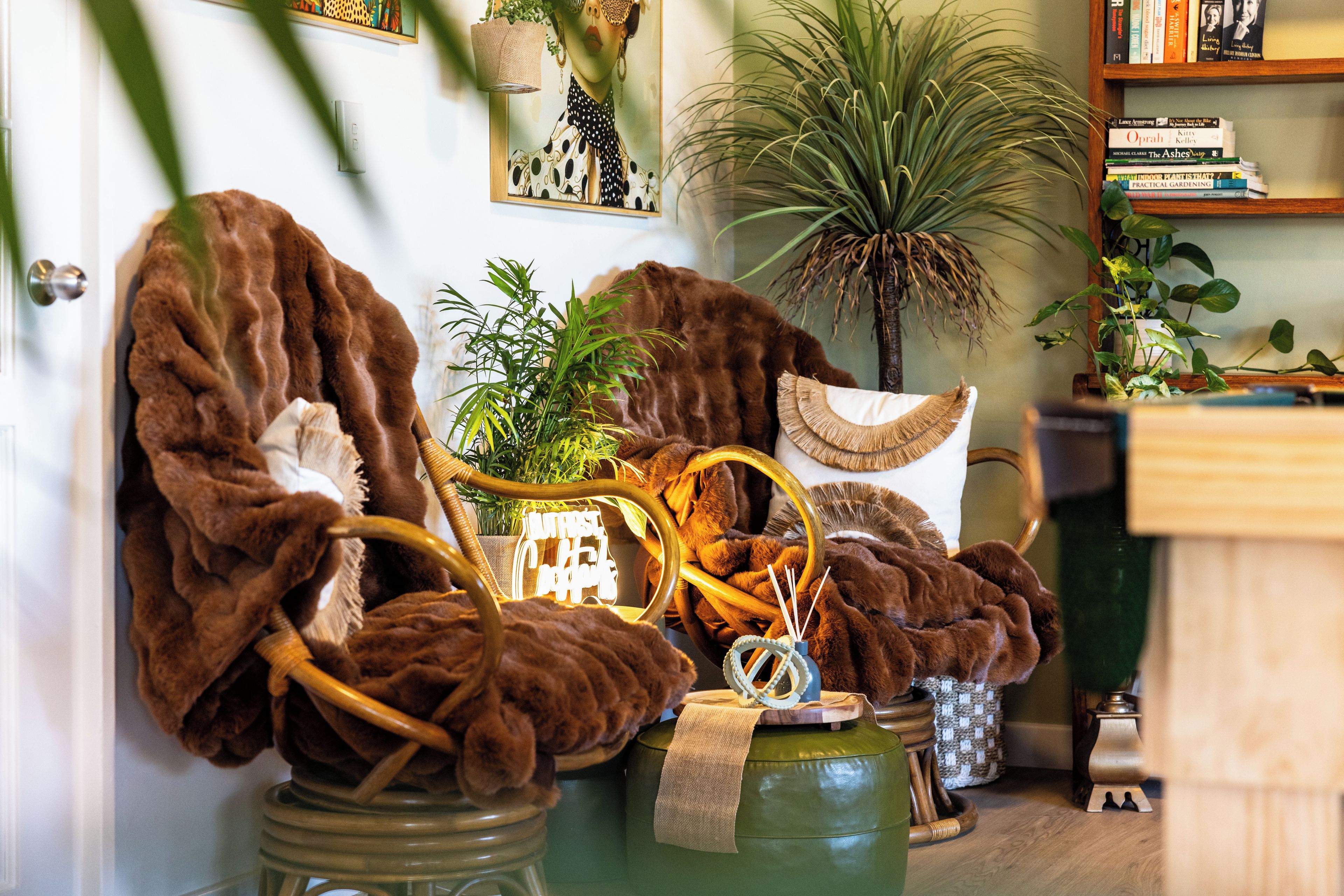Uma sala de estar aconchegante com um casaco de pele marrom grande sobre uma poltrona verde, um cesto de vime e uma planta em vaso.
