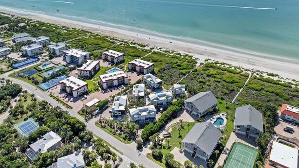 Vista aérea de um hotel à beira-mar, com vários edifícios, uma praia e uma vista desobstruída do oceano.