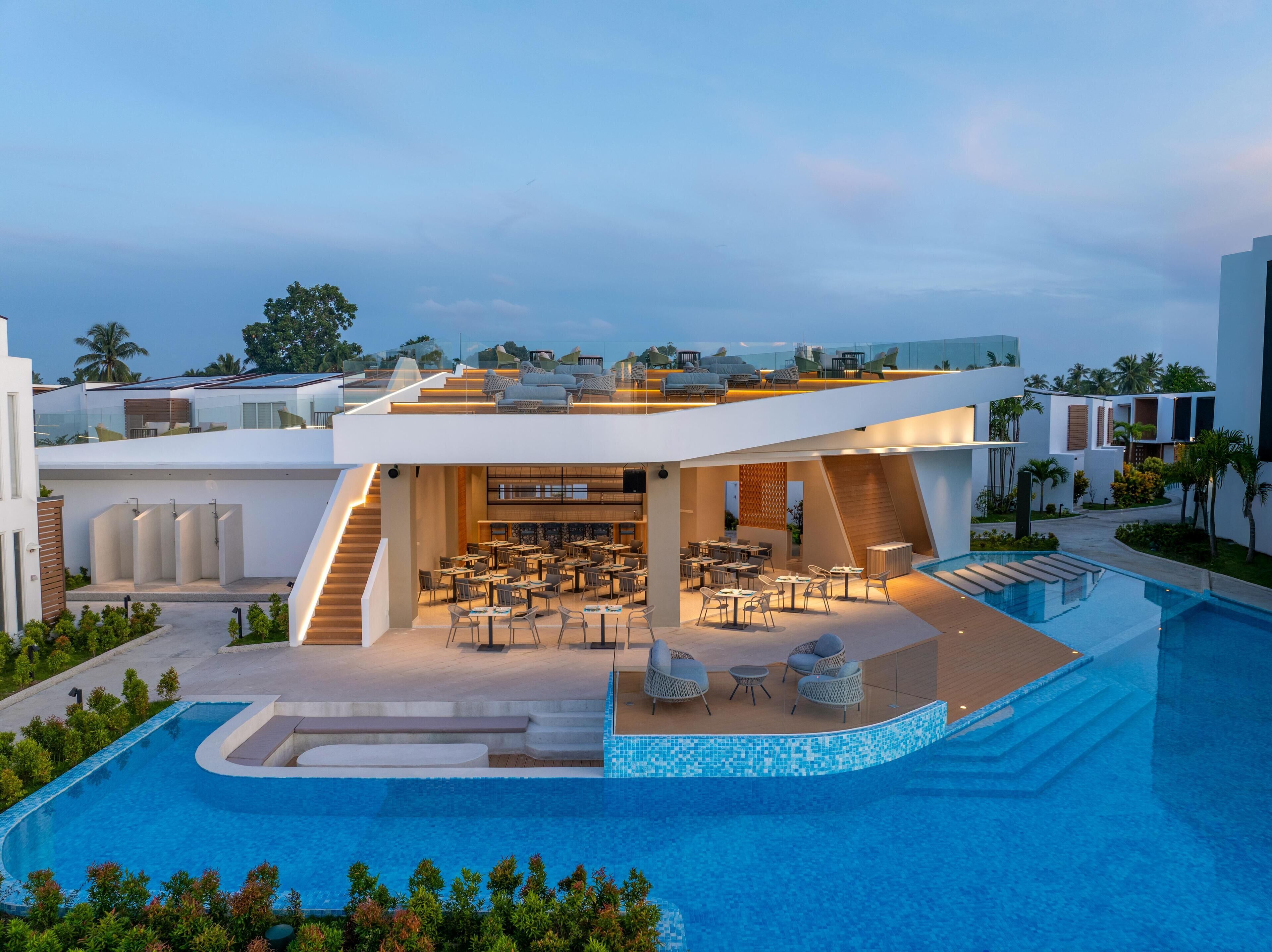 Um resort moderno com bar no terraço, piscina ao ar livre e área de refeições.