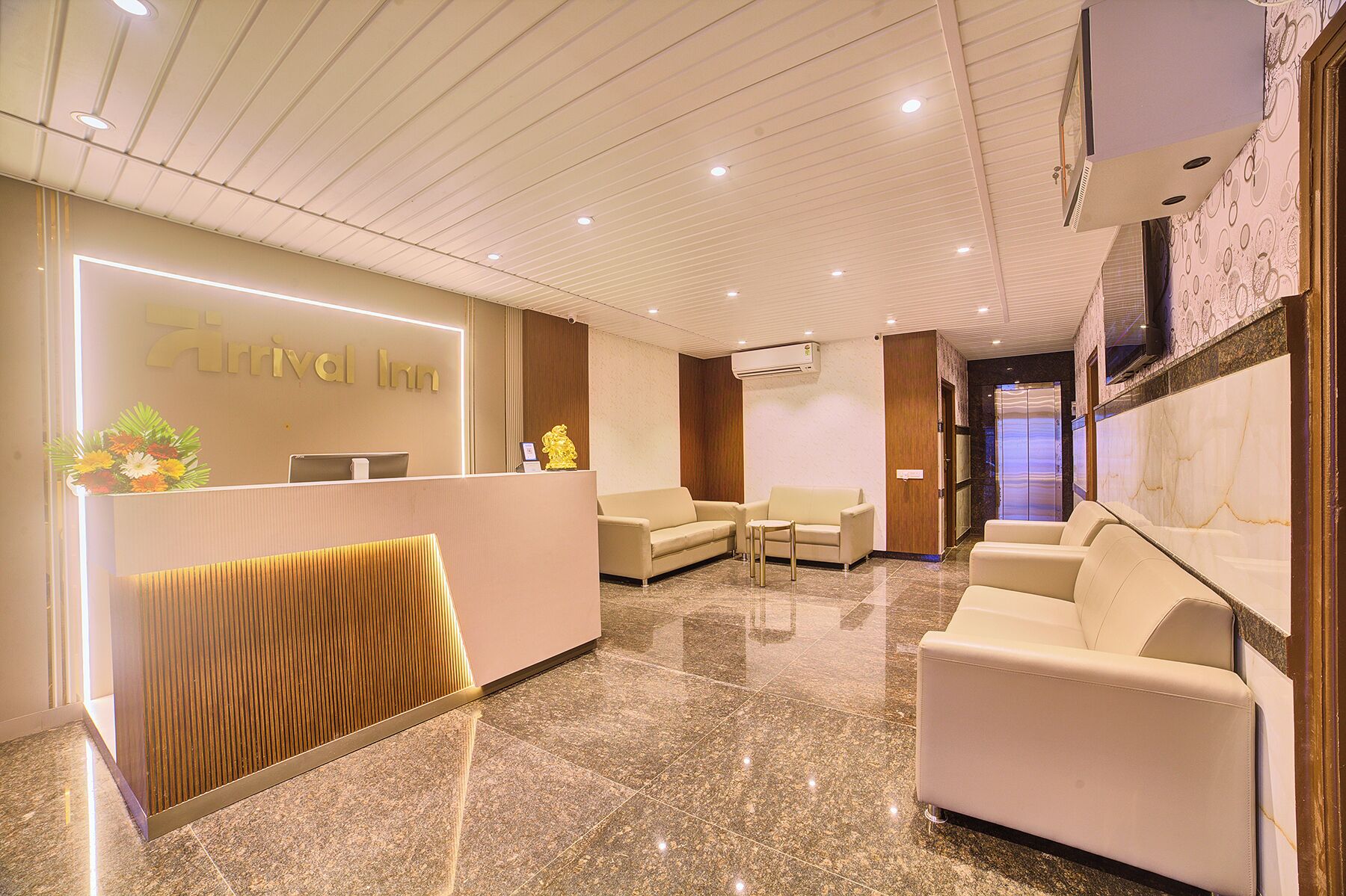 Uma área de recepção de hotel, com balcão, sala de espera com sofás e piso de mármore.