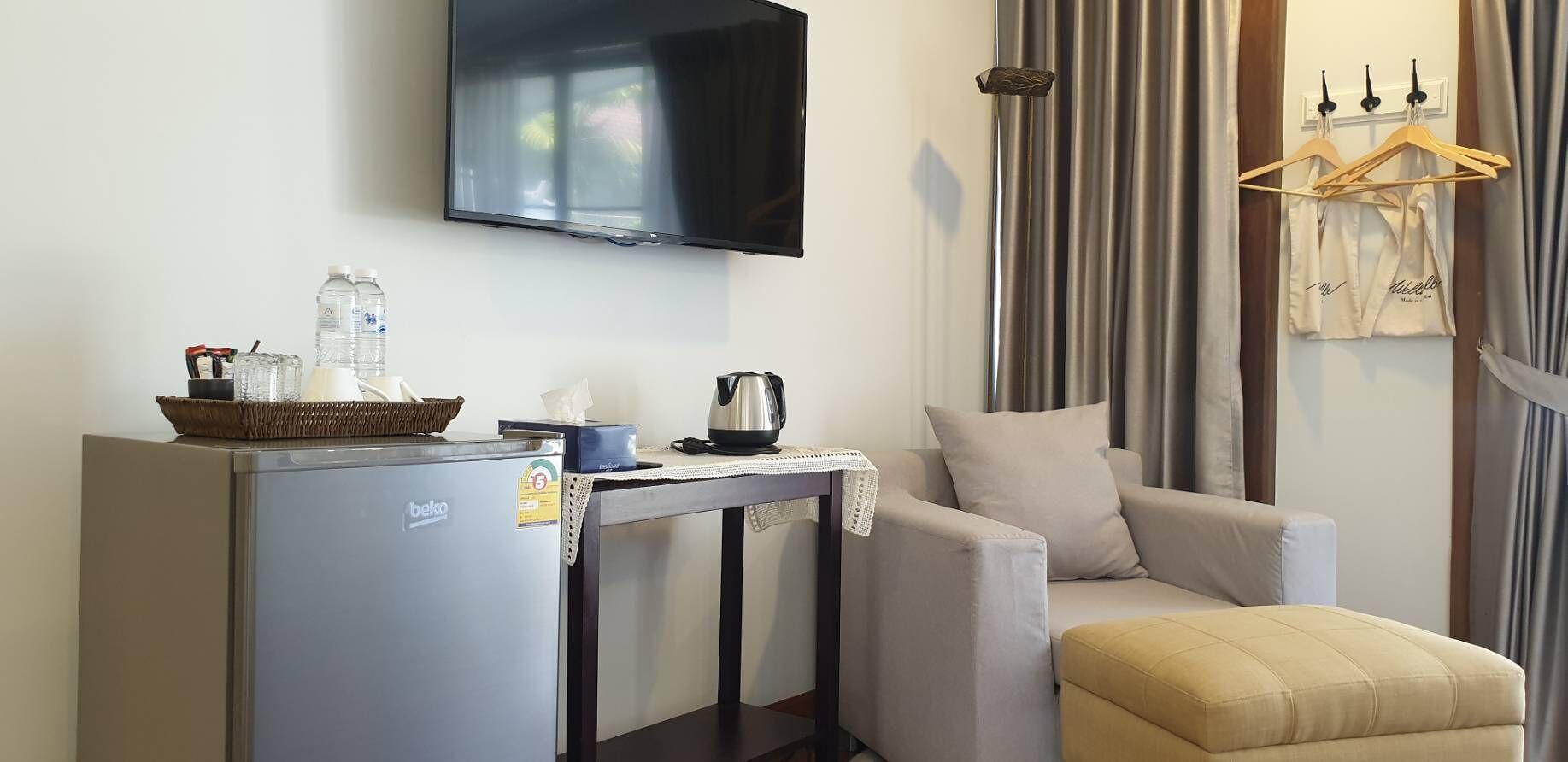 Um espaço compacto com cozinha compacta, televisão de tela plana, sofá e uma mesa com chaleira e cesta.
