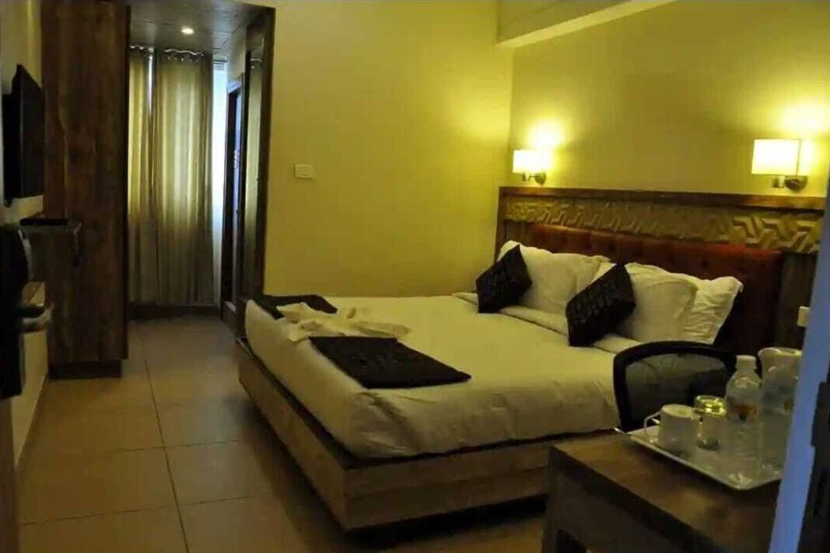 Quarto de hotel com cama, mesa de cabeceira e abajur.