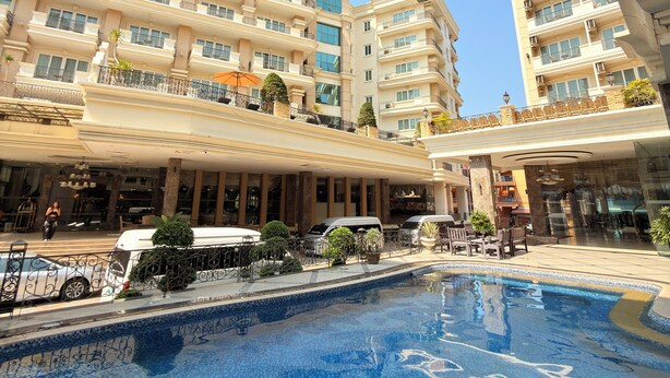 Um hotel com piscina, várias varandas e áreas de estar ao ar livre.