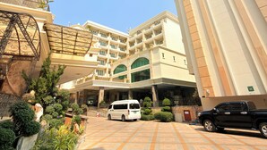 Um hotel com vários andares, um pátio central, entrada coberta e área de estacionamento.