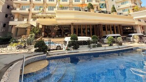Um hotel com vários andares, piscina, área de estar externa e entrada coberta.