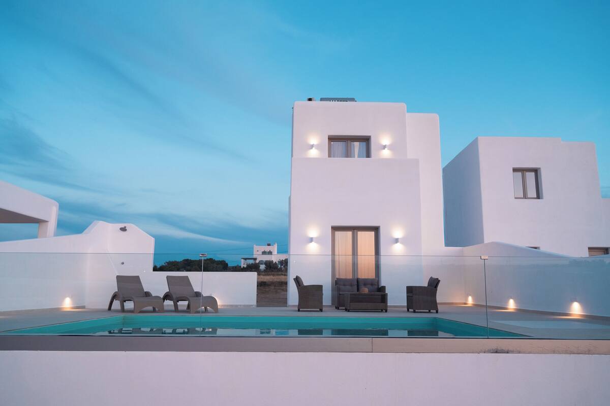 Um edifício moderno com piscina e espreguiçadeiras.
