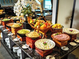 Buffet com diversos alimentos e um arranjo de flores decorativo.