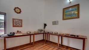 Um quarto com uma longa mesa de madeira, um relógio e quadros nas paredes.