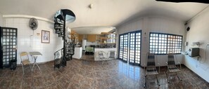 Cozinha espaçosa com área de jantar, escada e vista pelas janelas.