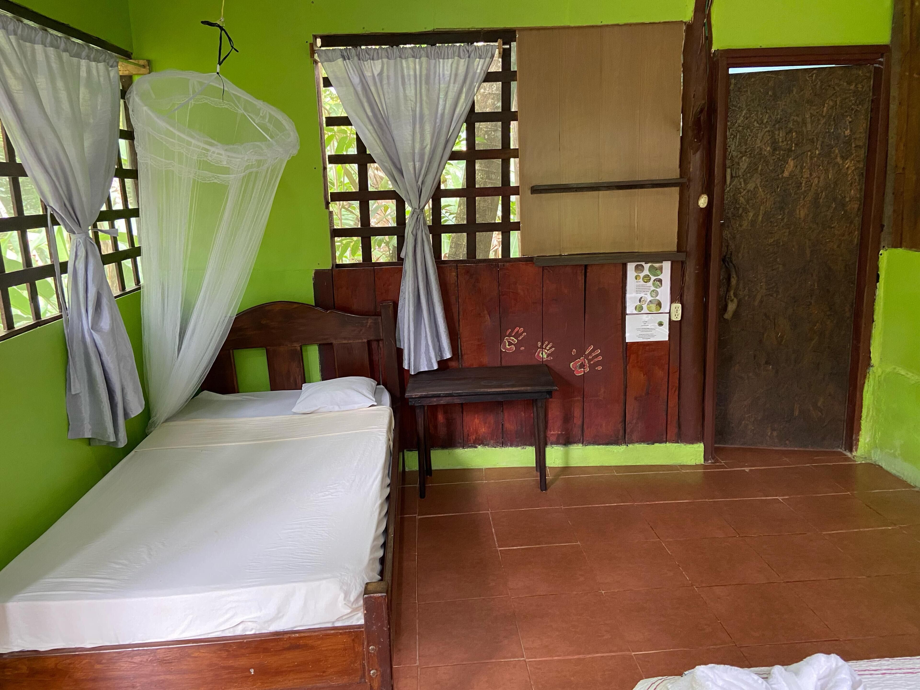Um quarto com uma cama, um banco e uma porta.