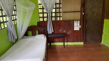 Um quarto com uma cama, um banco e uma porta.
