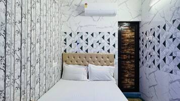 Quarto de hotel com cama, ventilador de teto e papel de parede estampado.