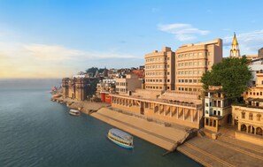 Paisagem urbana às margens do rio, com edifícios históricos, um cais de barcos e uma torre imponente.