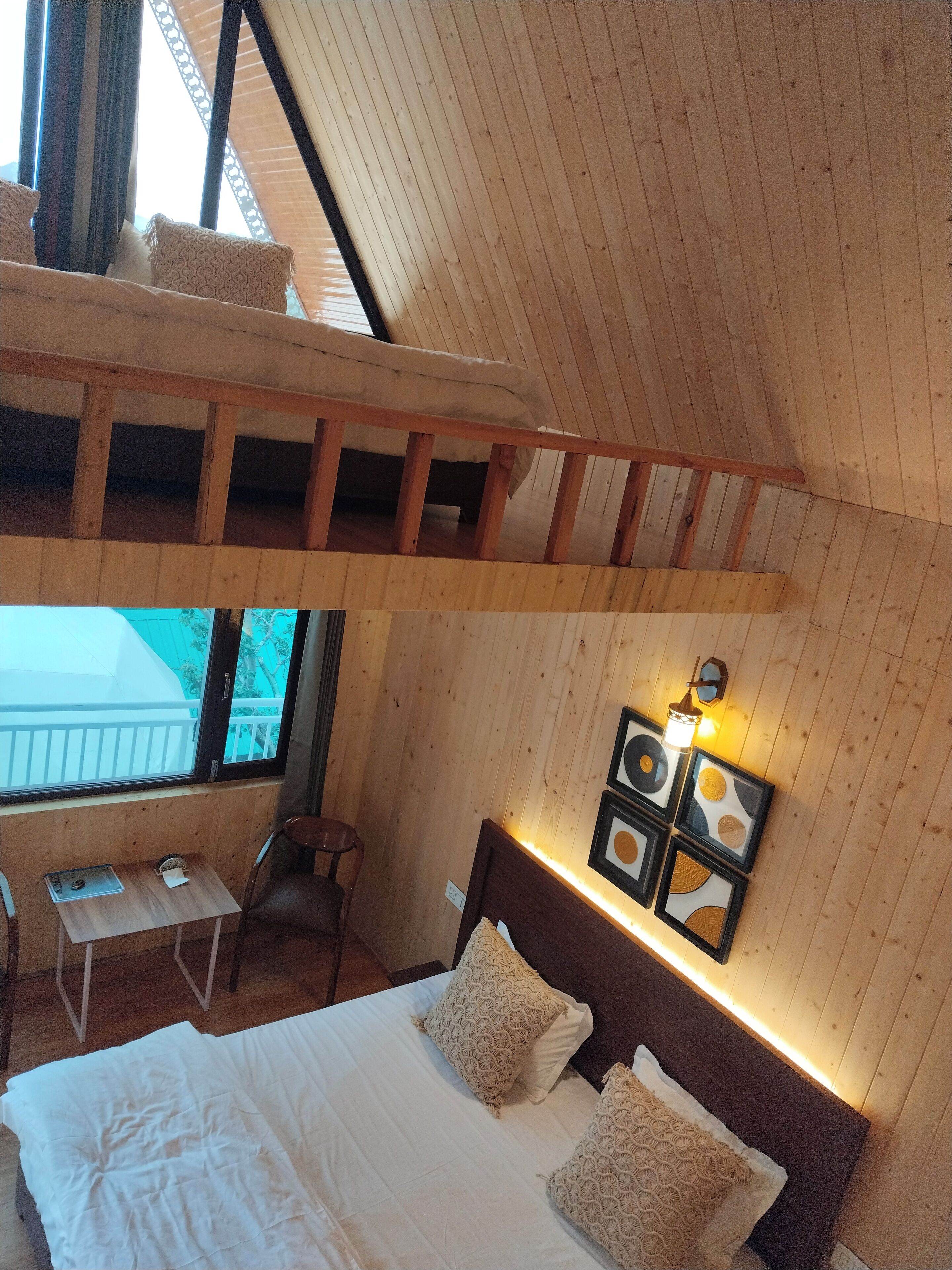 Quarto aconchegante com cama, escrivaninha e cadeira. Há uma janela com vista para uma varanda.
