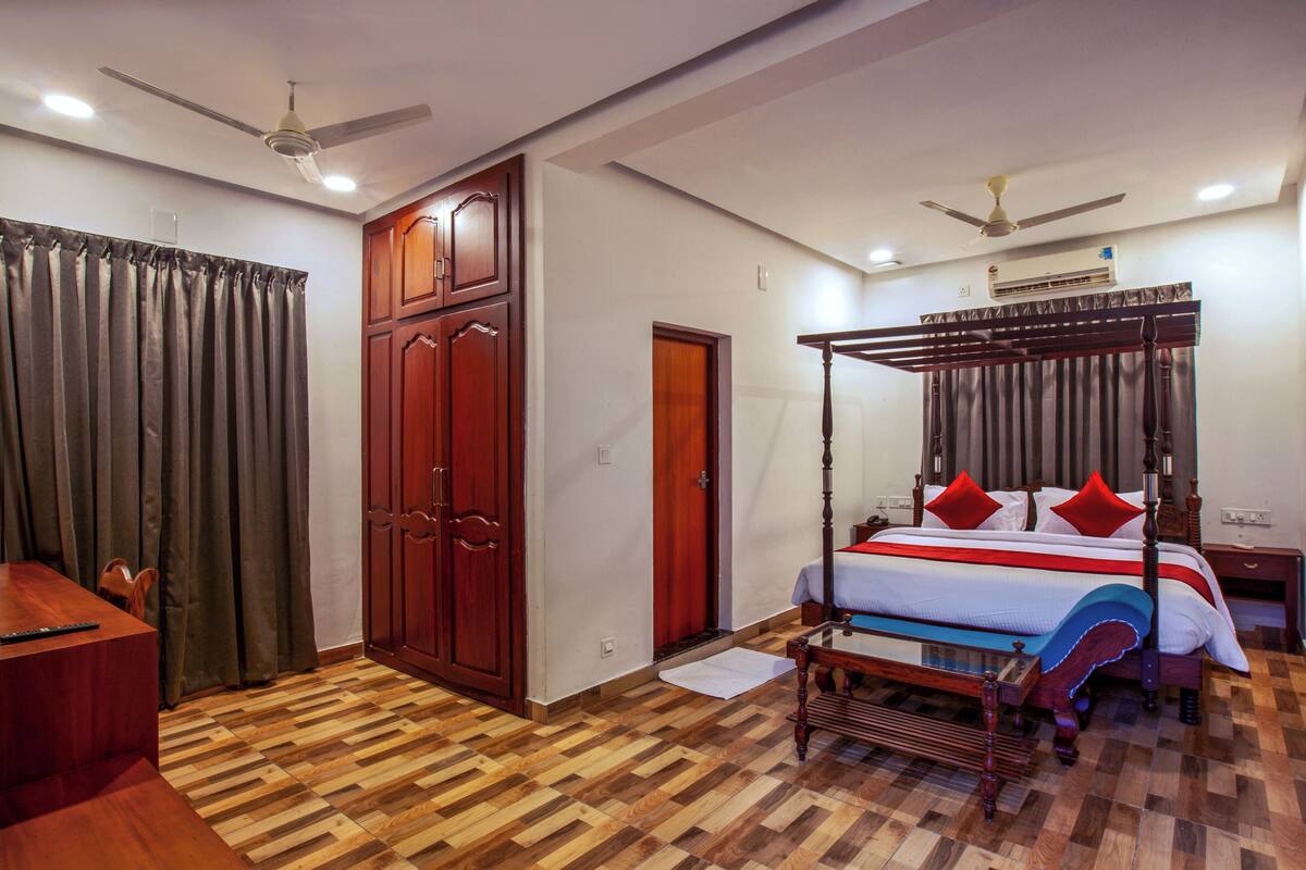 Quarto com cama de dossel, guarda-roupa de madeira, ventoinhas de teto e chão de madeira.