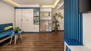 Uma sala de estar moderna com um sofá azul, uma mesinha, uma televisão e um armário com portas de vidro.