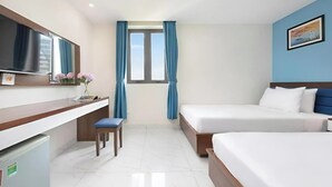 Quarto de hotel com cama, escrivaninha, cadeira, televisão e janela com cortinas.
