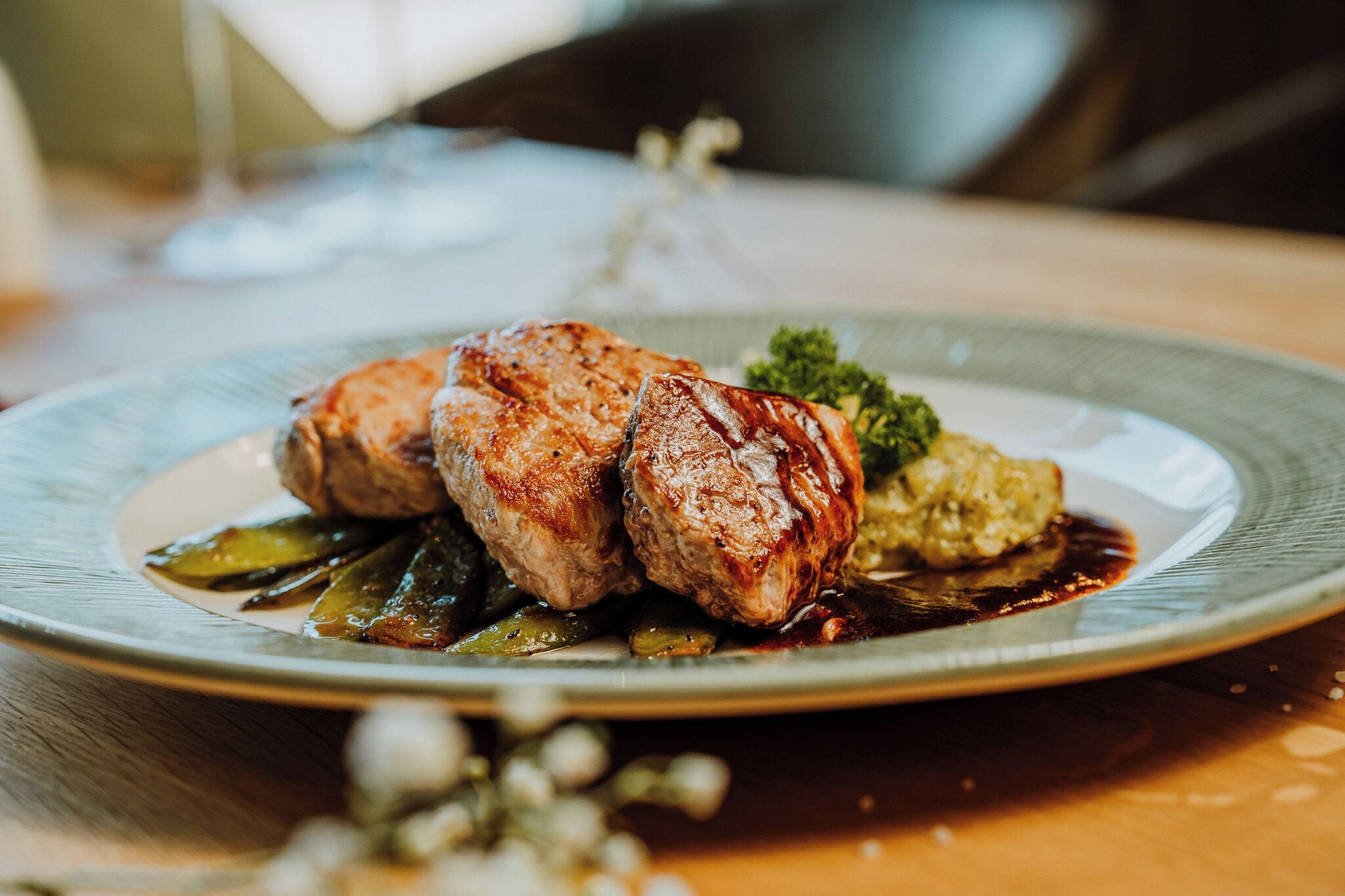 Um prato com carne grelhada, legumes e molho.