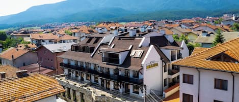 Um hotel com vários andares, varandas e vista para a cidade e montanhas ao redor.