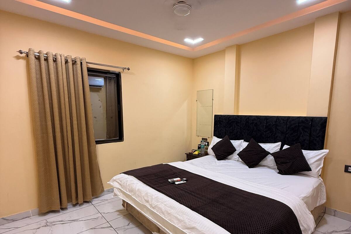Quarto com cama, cortinas, mesa de cabeceira e ventoinha no teto.