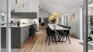Cozinha moderna com armários cinza, ilha central e iluminação pendente.