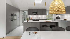 Cozinha moderna com ilha central, armários cinzas e uma luminária pendente grande.