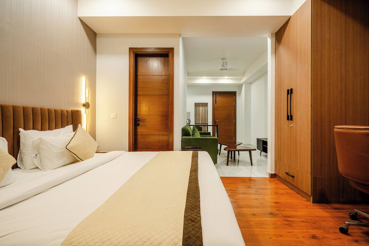 Quarto de hotel com cama, escrivaninha, cadeira e guarda-roupa.