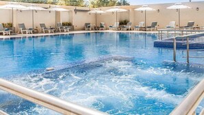 Piscina com espreguiçadeiras e guarda-sóis.