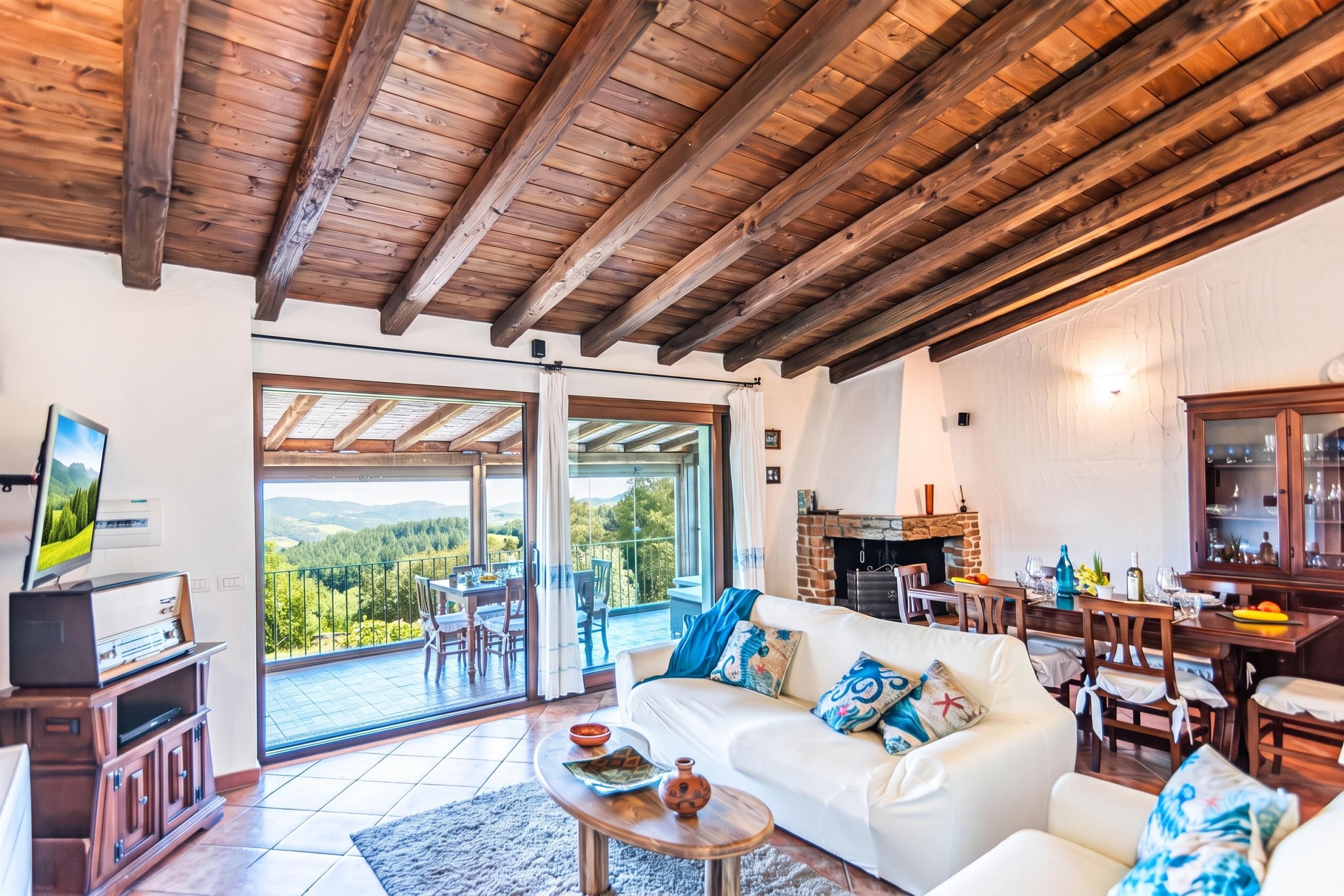 Uma sala de estar espaçosa com sofá branco, vigas de madeira, lareira e área de jantar com vista para o campo.