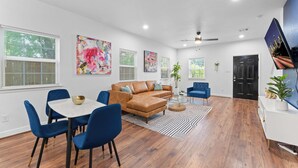 Uma sala de estar moderna com um sofá seccional marrom, cadeiras azuis, uma mesa de centro branca e uma porta preta.