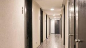 Um corredor comprido e estreito com piso de madeira e paredes bege.