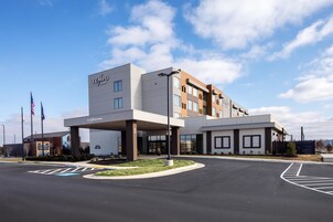 Um hotel moderno com telhado plano, várias janelas e uma placa com a inscrição 'TEMPO by Hilton'.