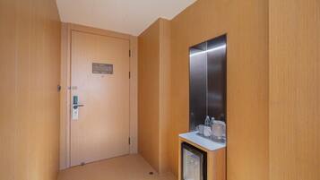 Um corredor com paredes de madeira, uma porta com uma placa e um balcão pequeno com um espelho e um quadro emoldurado.