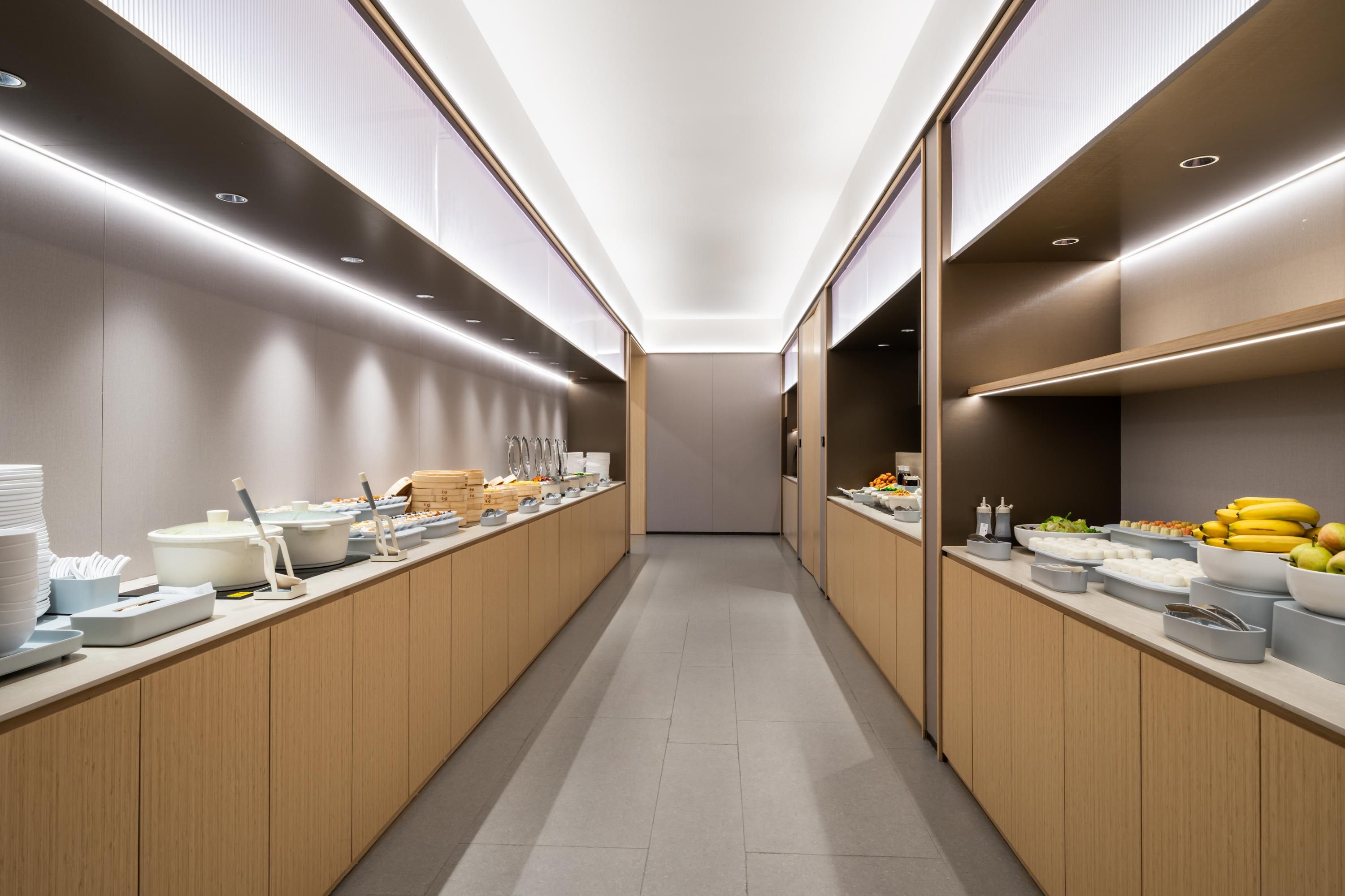 Um corredor moderno e bem iluminado, com um balcão comprido exibindo diversos alimentos e utensílios de cozinha.