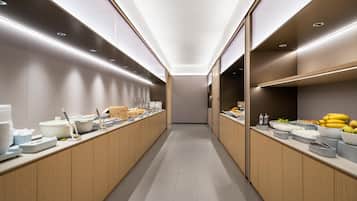 Um corredor moderno e bem iluminado, com um balcão comprido exibindo diversos alimentos e utensílios de cozinha.